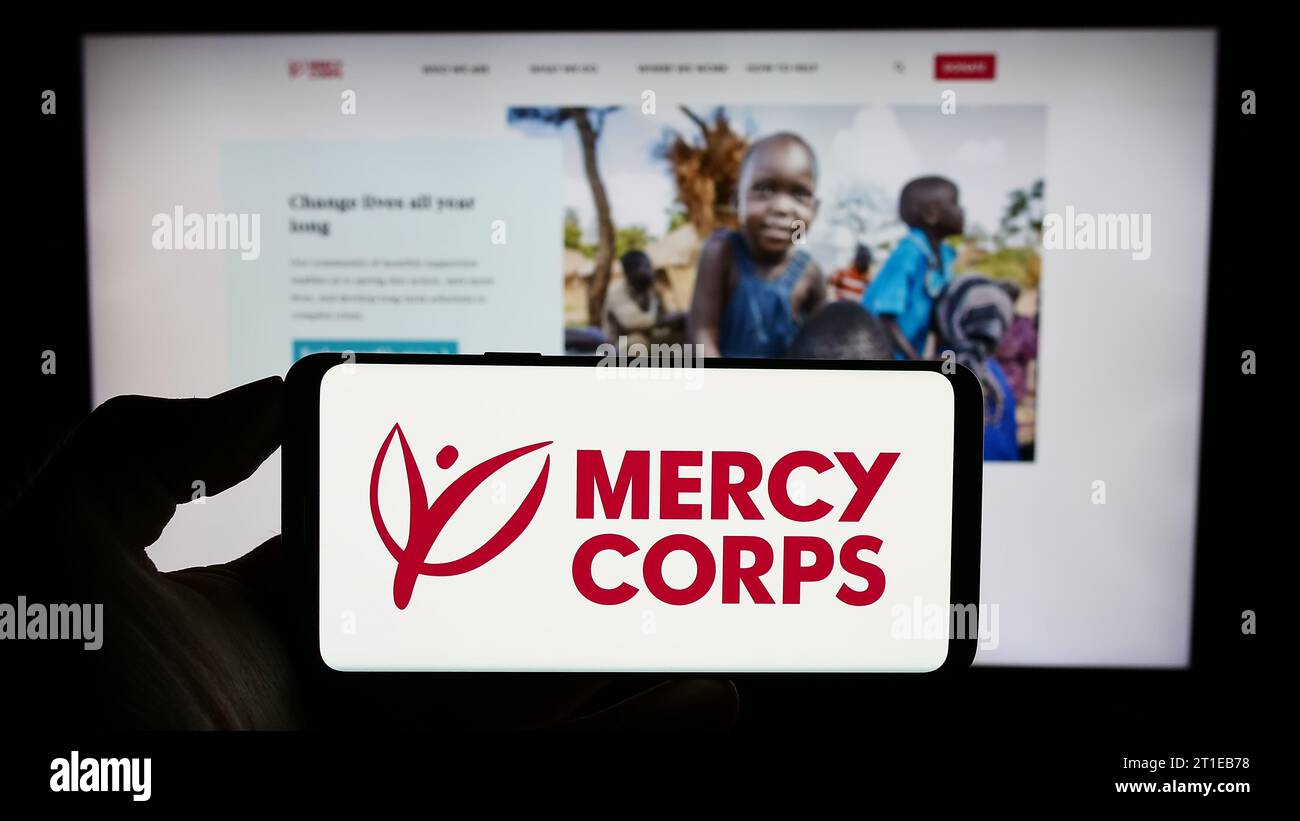 Person holding mobile phone with logo of American humanitarian aid ...