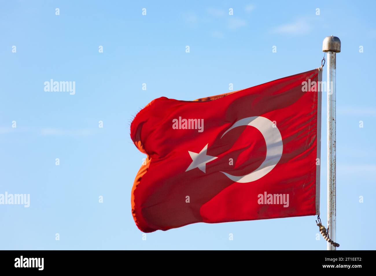 Turkish Flag aka Turk Bayragi on the flagpole isolated on blue sky ...