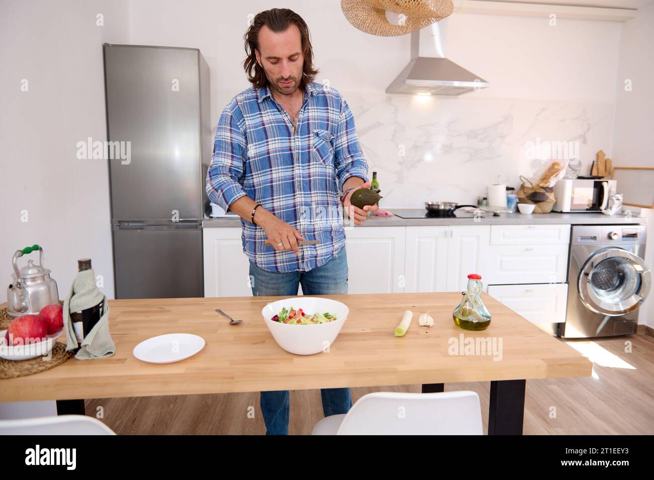 Handsome male chef dressed in casual clothes, cooking a healthy salad ...