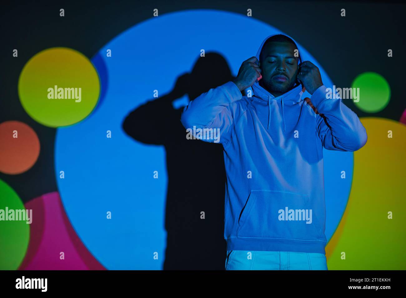 handsome man putting on hood with closed eyes in digital projector ...