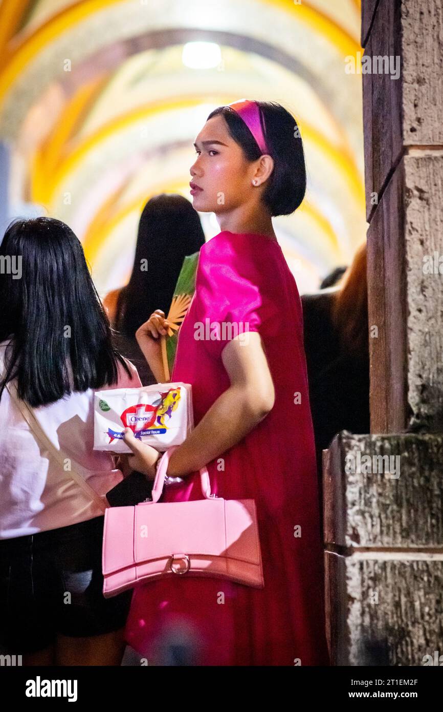 A young beautiful Filipino girl, stylishly dressed, fans herself in the ...