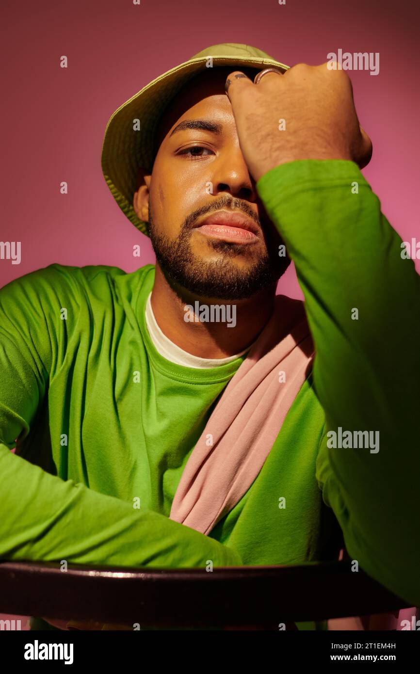 handsome young man with beard in green hat with palm on his face ...
