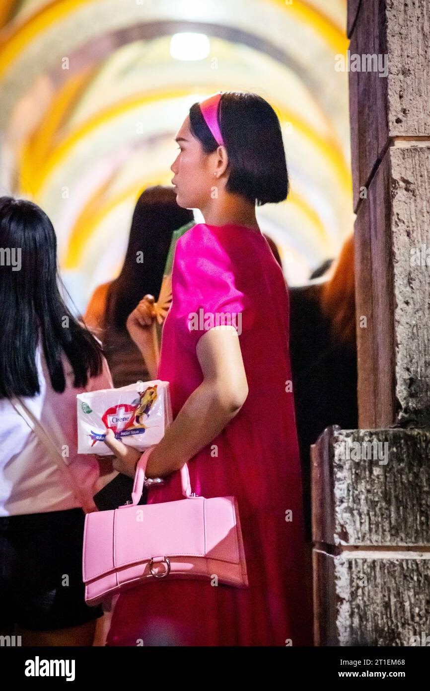 A young beautiful Filipino girl, stylishly dressed, fans herself in the ...