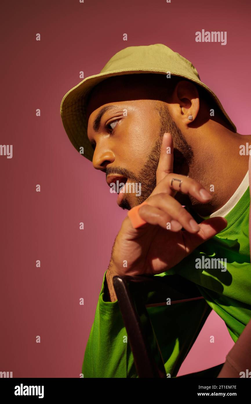 young good looking man posing in profile on chair with mouth slightly ...