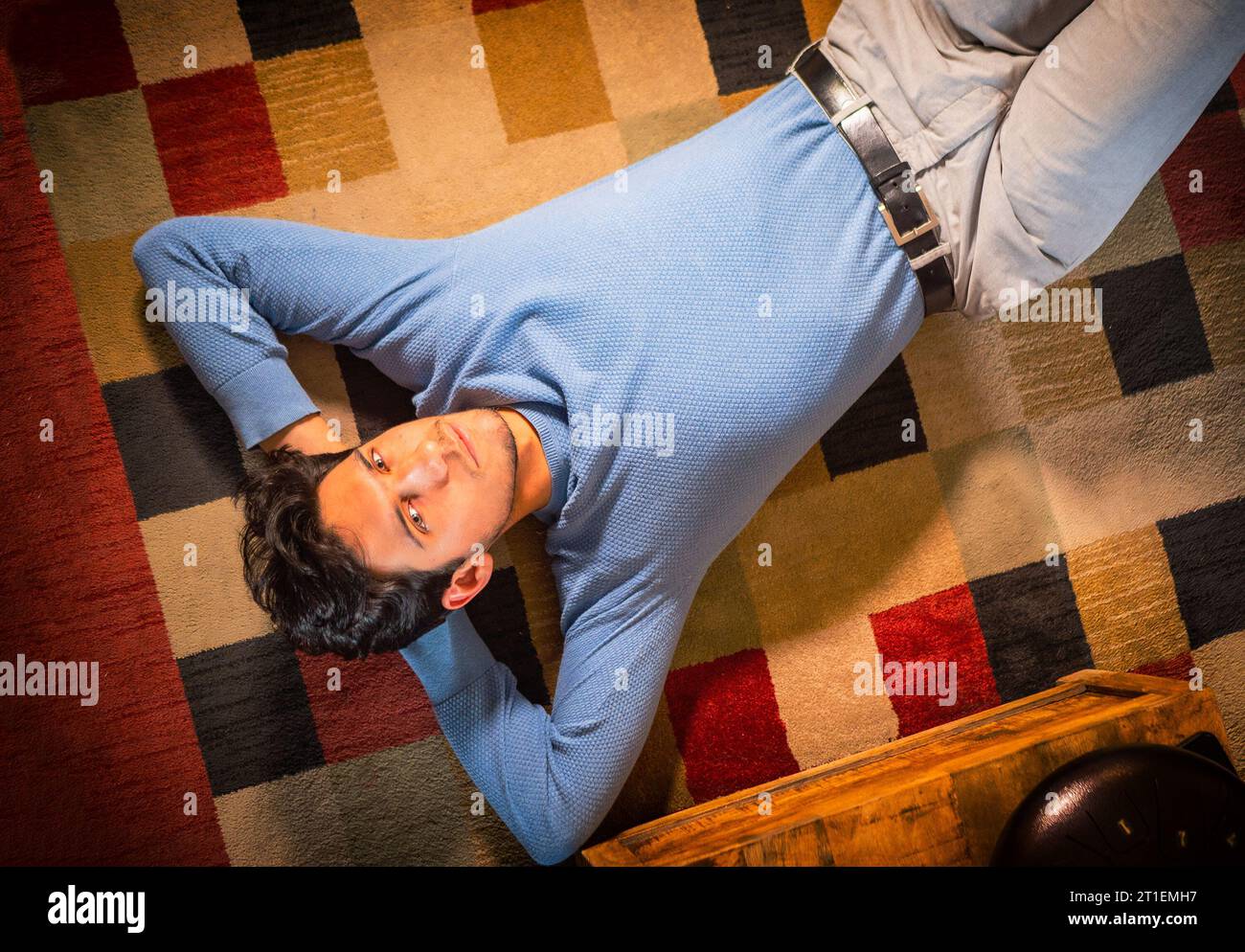Cool dark-haired handsome young man laying on the floor over colorful ...