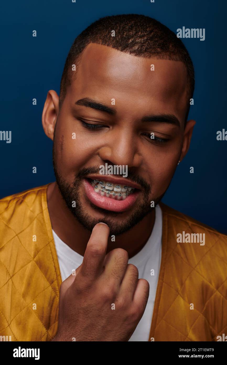 smiley african american male model with braces looking down with finger ...