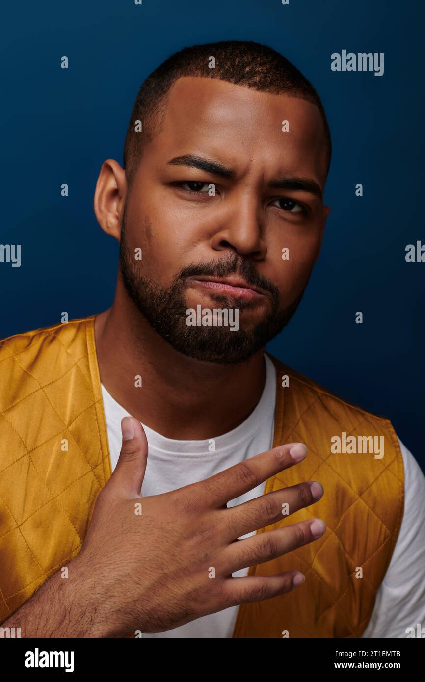 portrait of handsome african american man looking at camera with hand near face, fashion concept ...