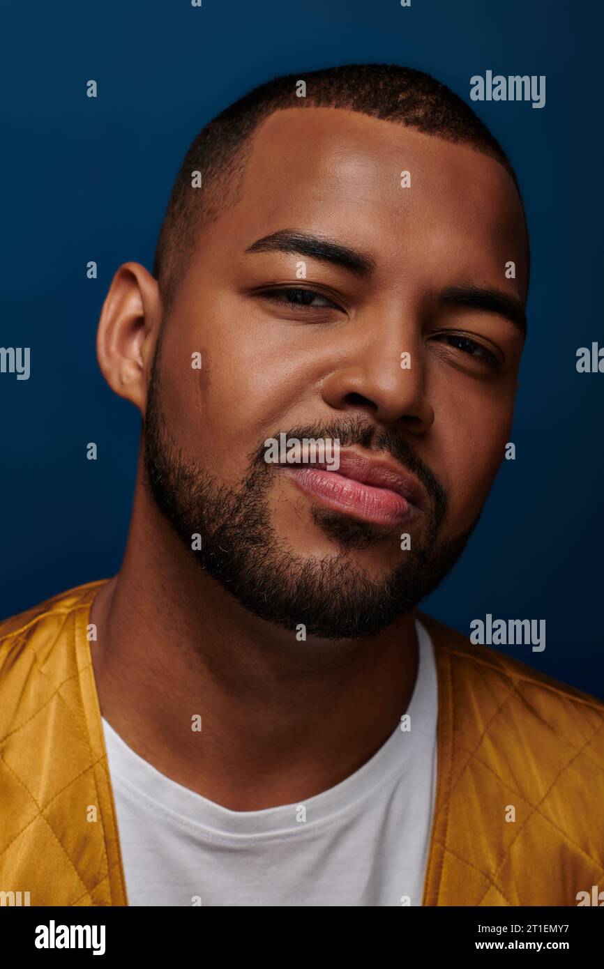 handsome african american man looking at camera and slightly smiling at ...