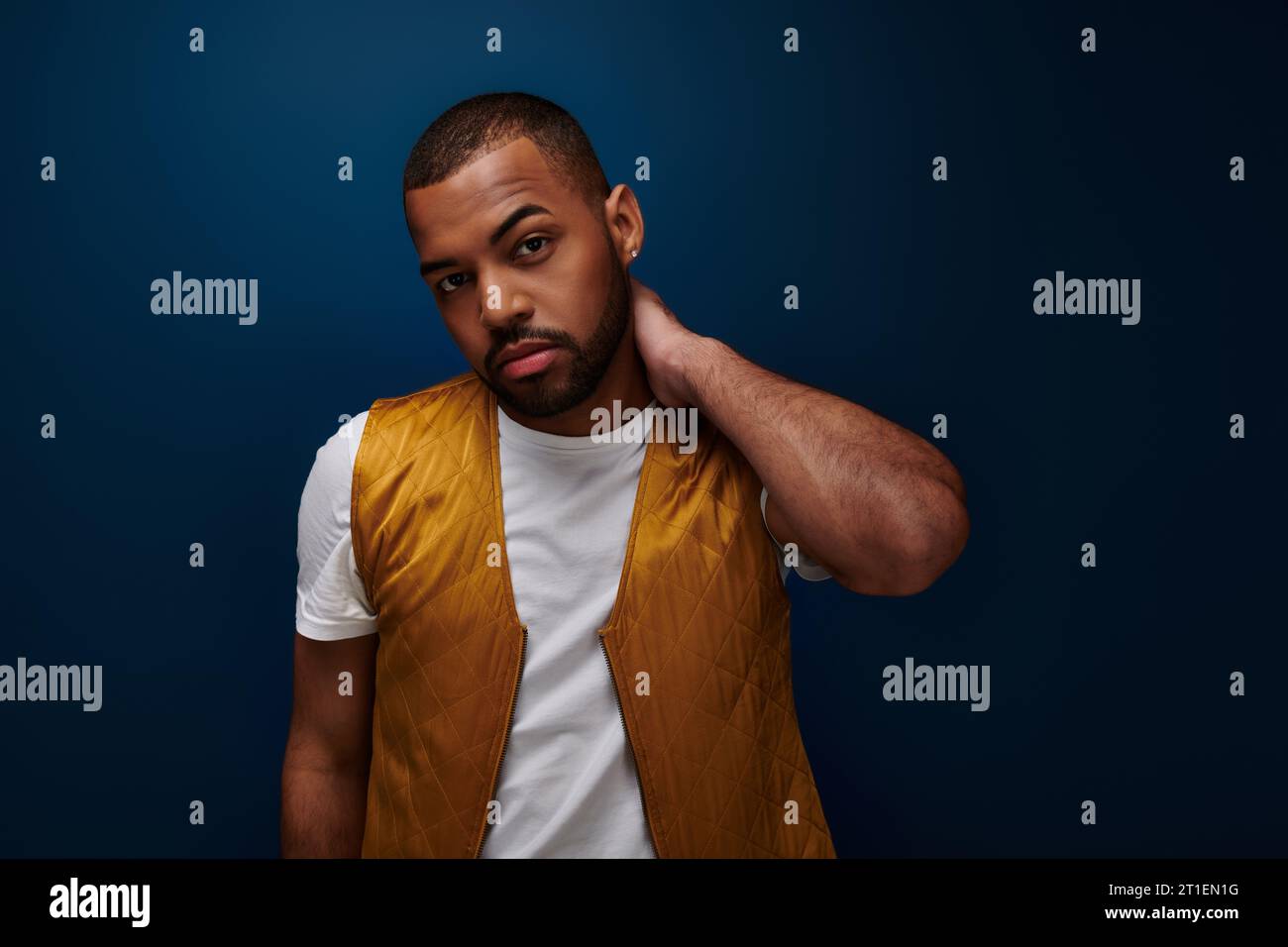 handsome young man in trendy vest with hand behind his neck and raised ...