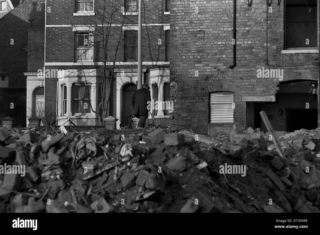 Smartly dressed elderly man walking amongst demolition rubble on a ...