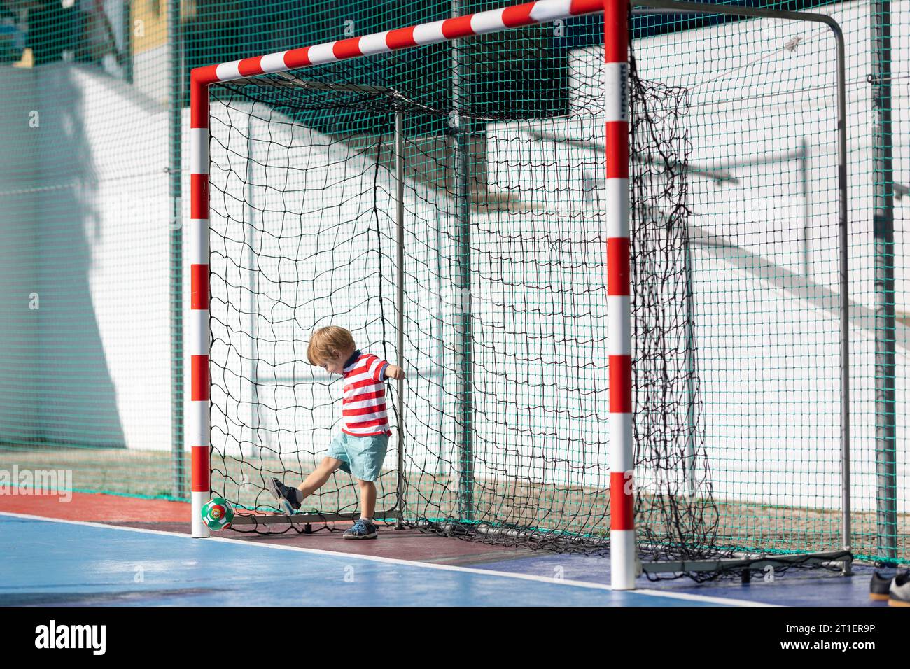 Little blonde smiling boy playing soccer - standing in the gates and ...
