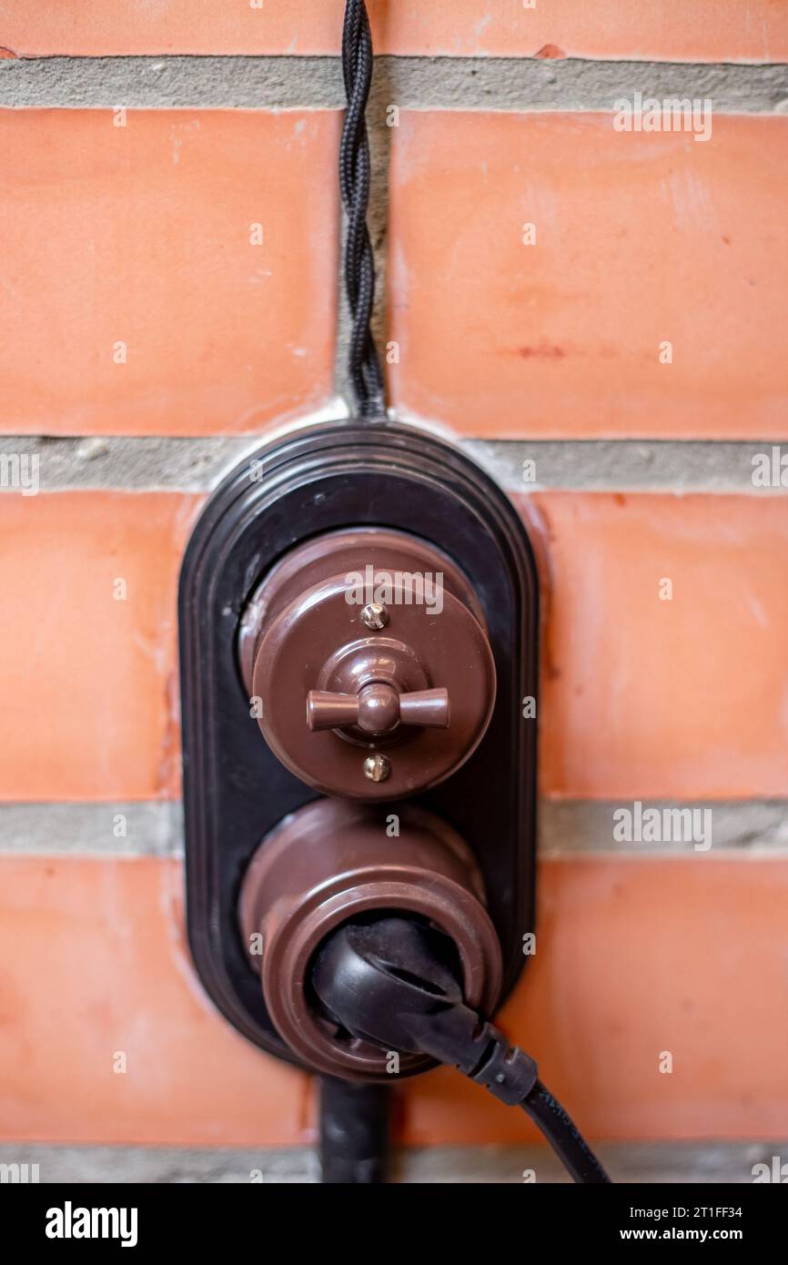 Modern retro switch and socket with twisted wire on a brick wall ...