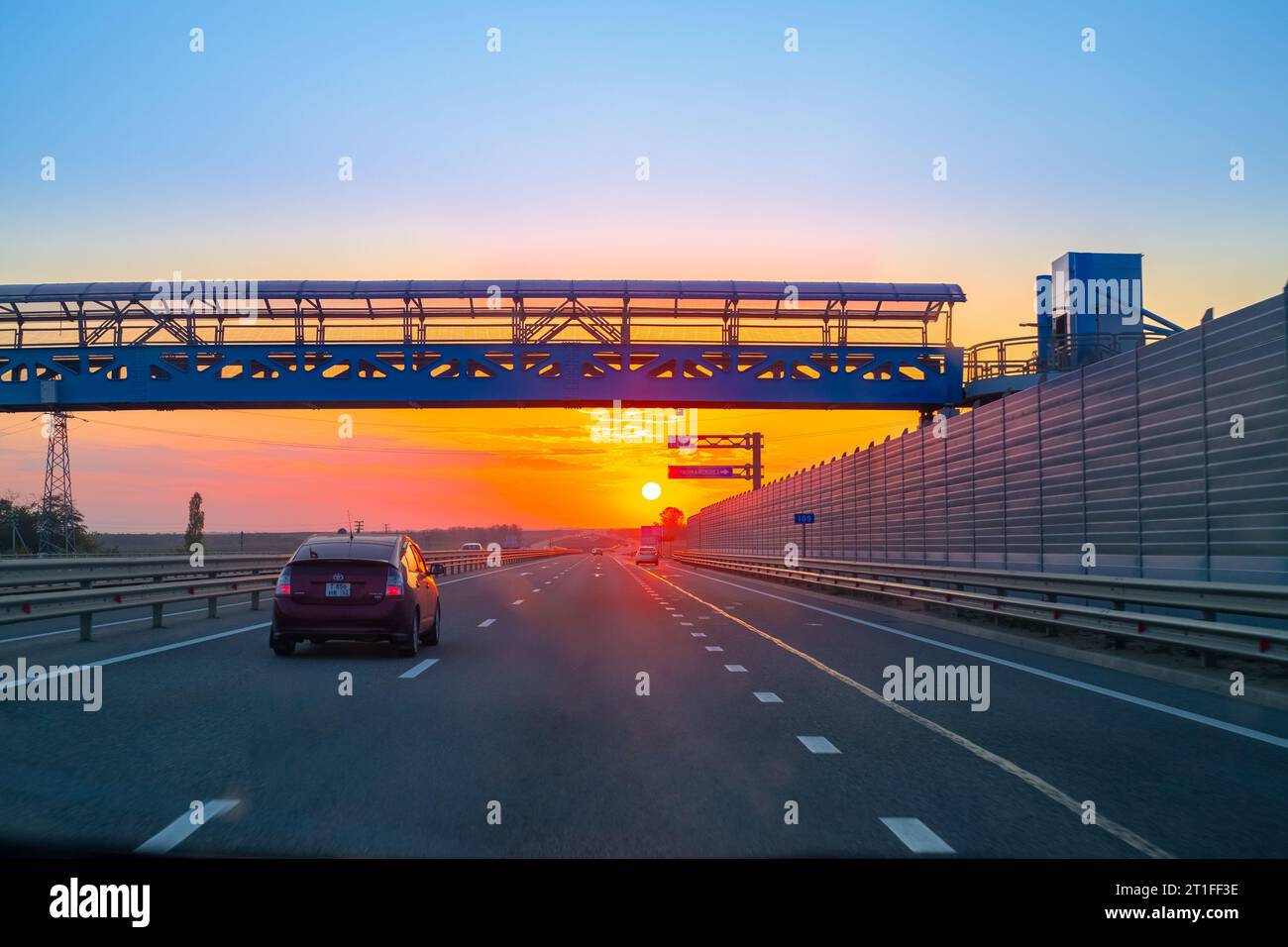 A road with an elevated pedestrian crossing, a noise-reducing screen ...