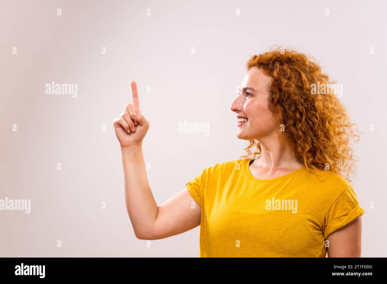 Portrait of beautiful ginger woman pointing on gray background Stock ...