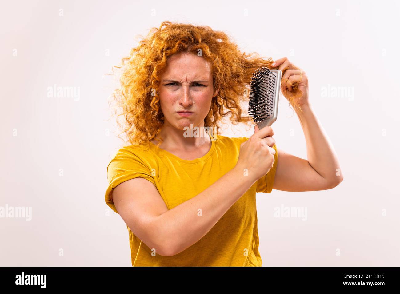 Angry ginger woman holding hairbrush and combing her curly hair Stock ...