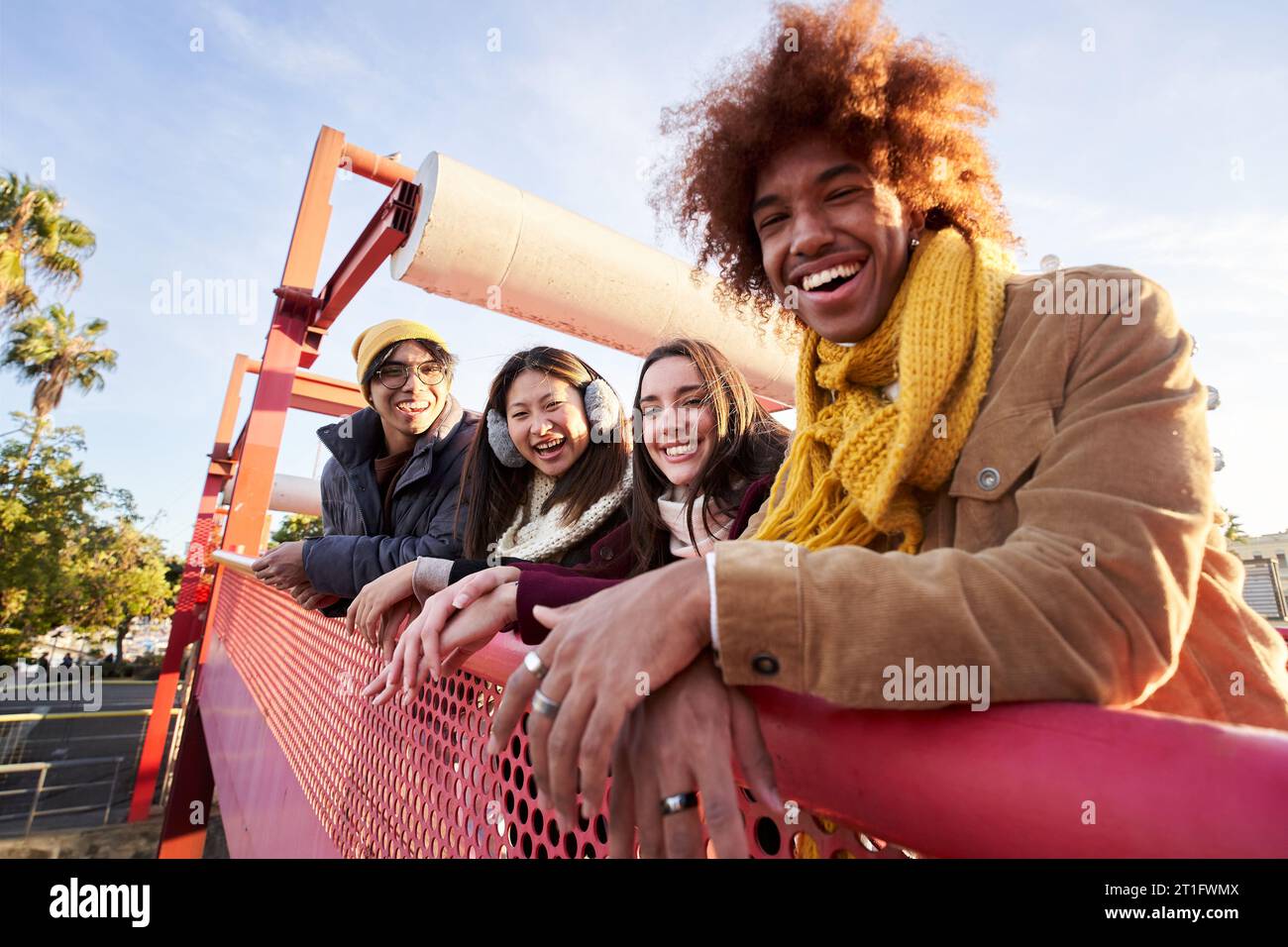 Multi-ethnic group smiling friends gathered street leaning on railing ...