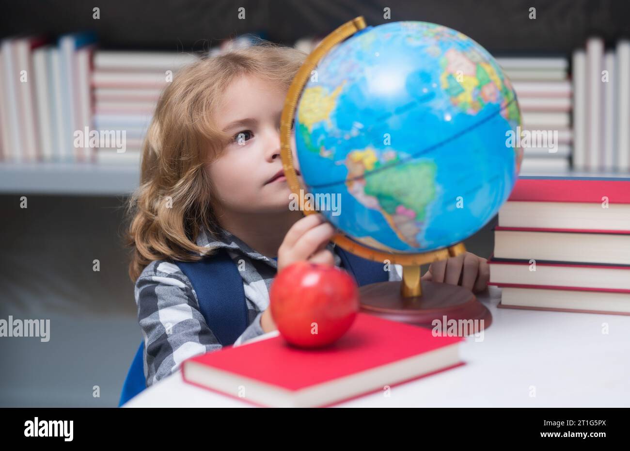 School pupil looking at globe in library, geography lesson. School and ...