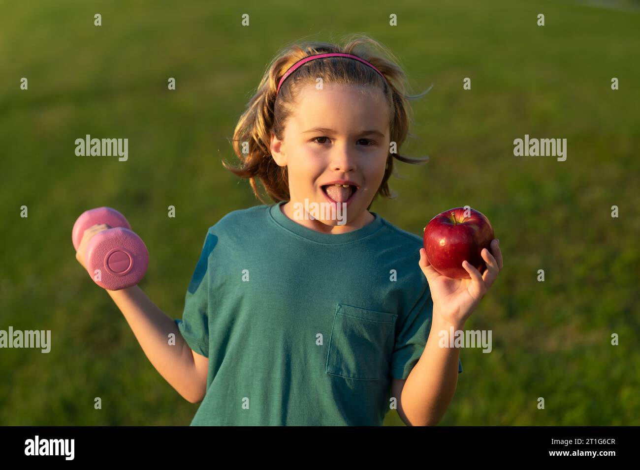 Healthy sporty child with apple and dumbbell outdoor in park. Child boy ...