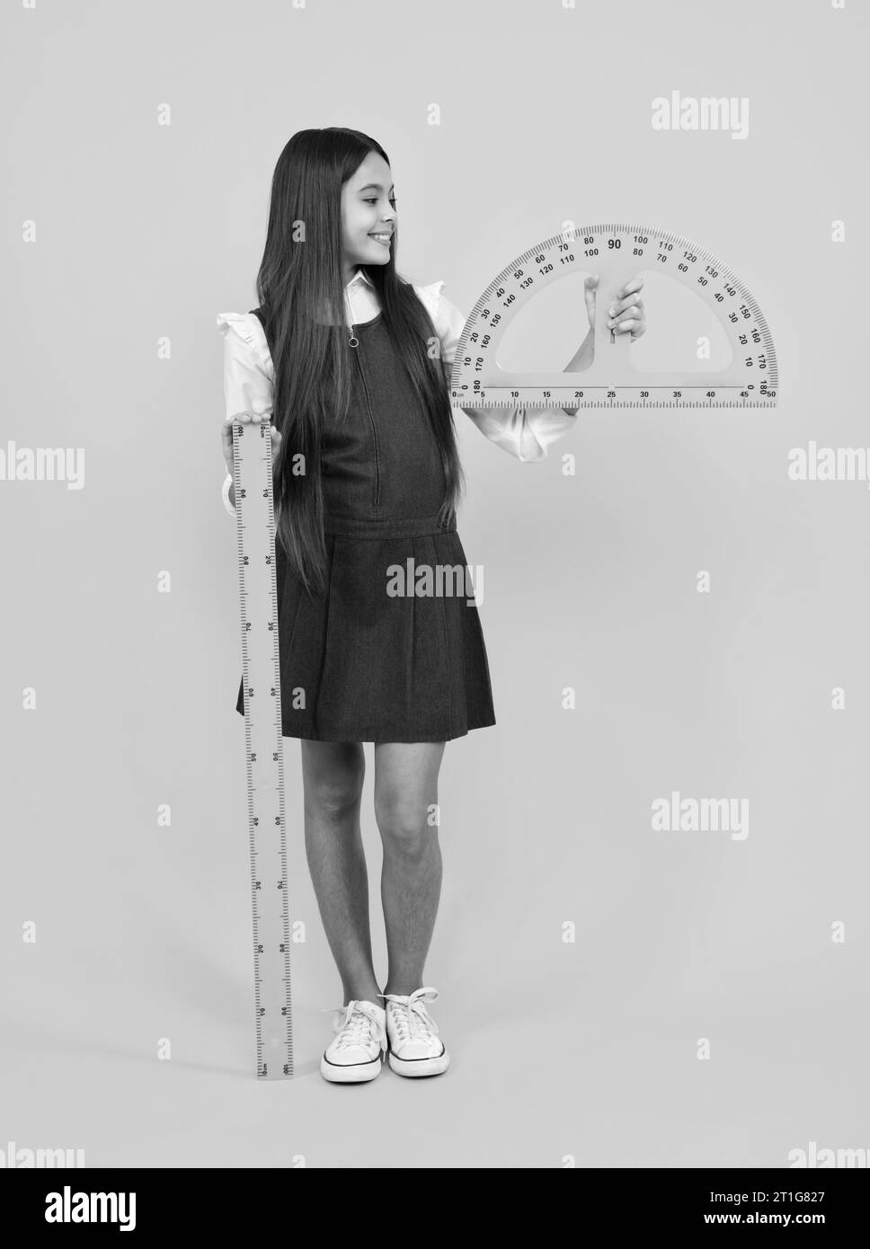 Back to school. School girl hold ruler measuring isolated on yellow ...