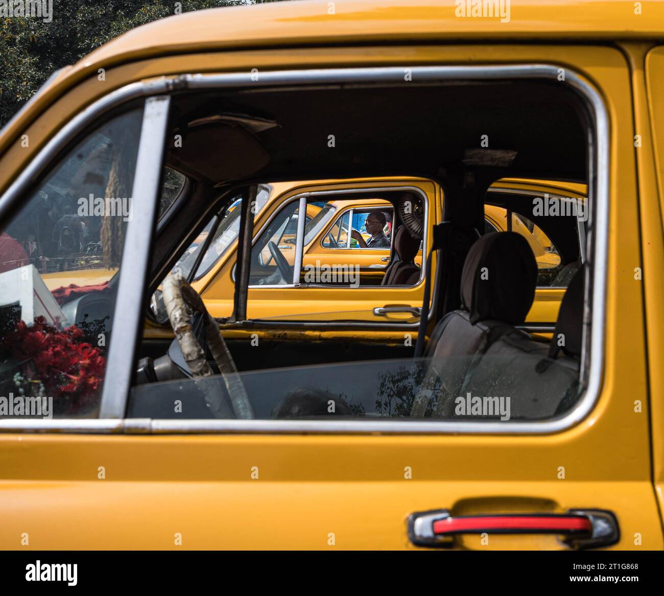 A yellow taxi cab with its interior visible looking out from the window ...