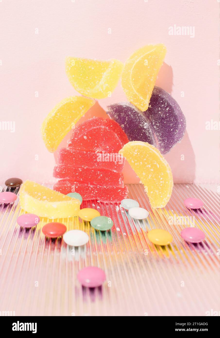 Colorful jelly and skittles candys against pastel pink and shiny ...