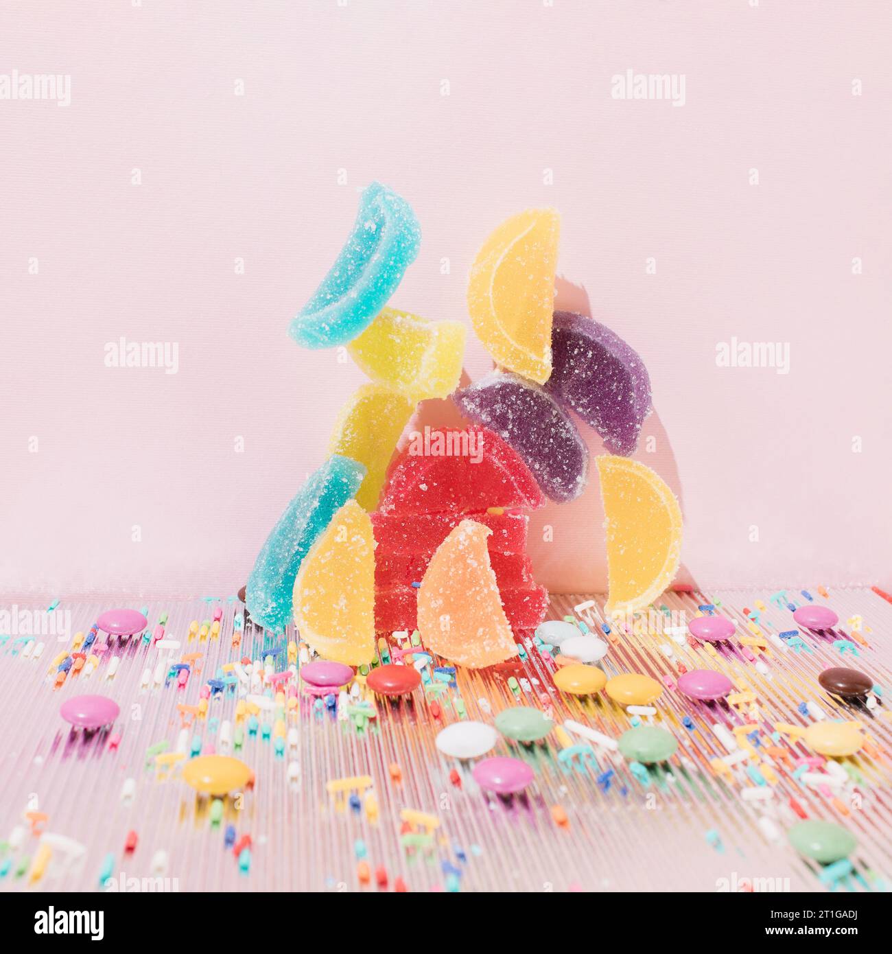 Colorful jelly and skittles candys against pastel pink and shiny ...