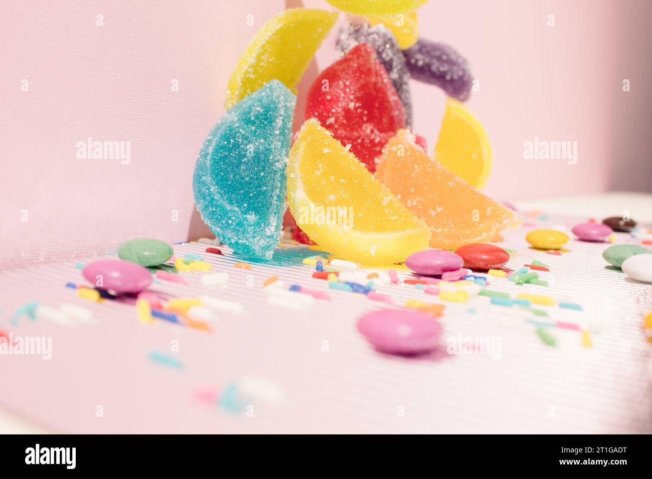 Colorful jelly and skittles candys against pastel pink and shiny ...