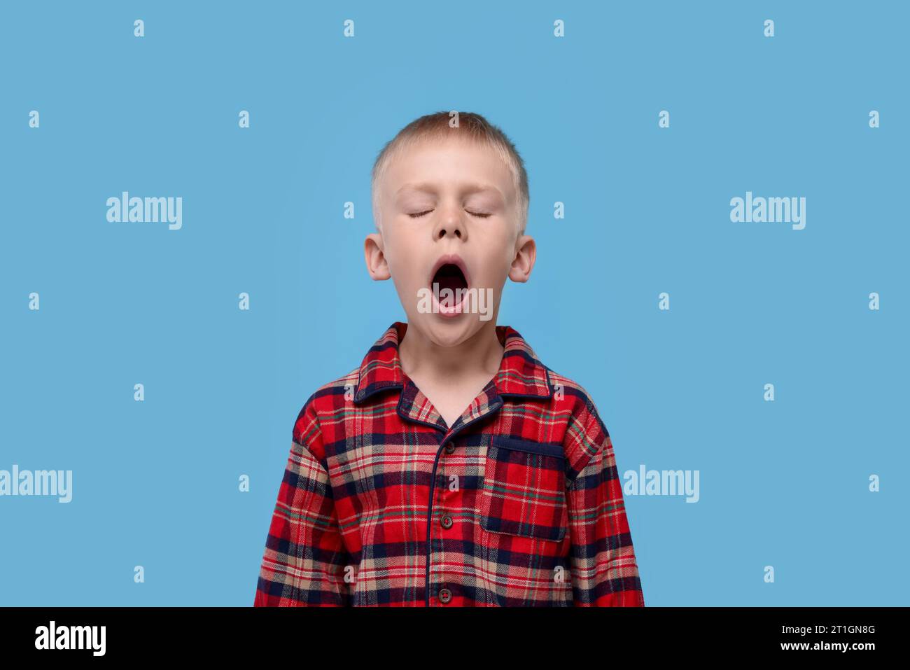 Sleepy boy yawning on light blue background. Insomnia problem Stock ...