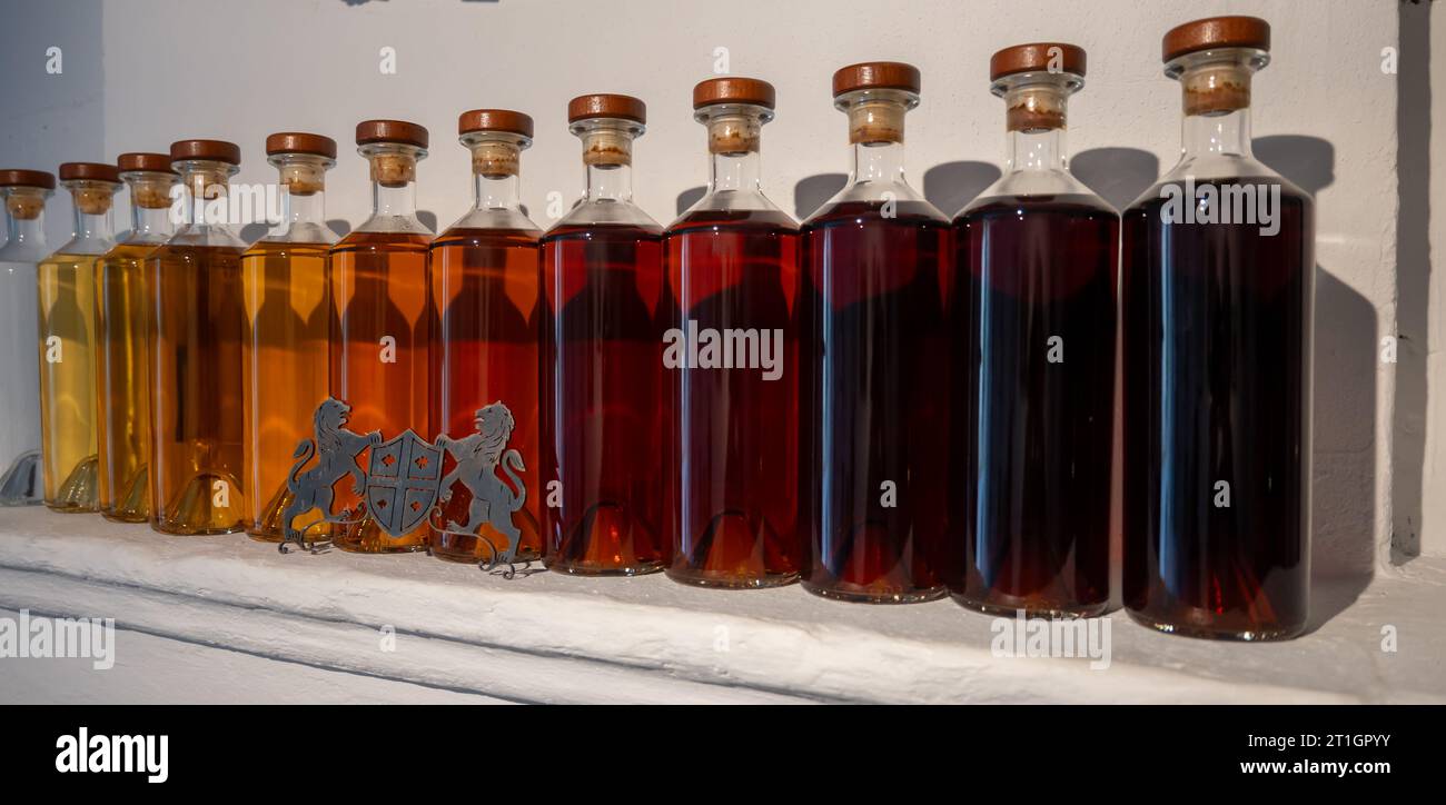 Different colours and ages of cognac spirits in bottles in distillery ...