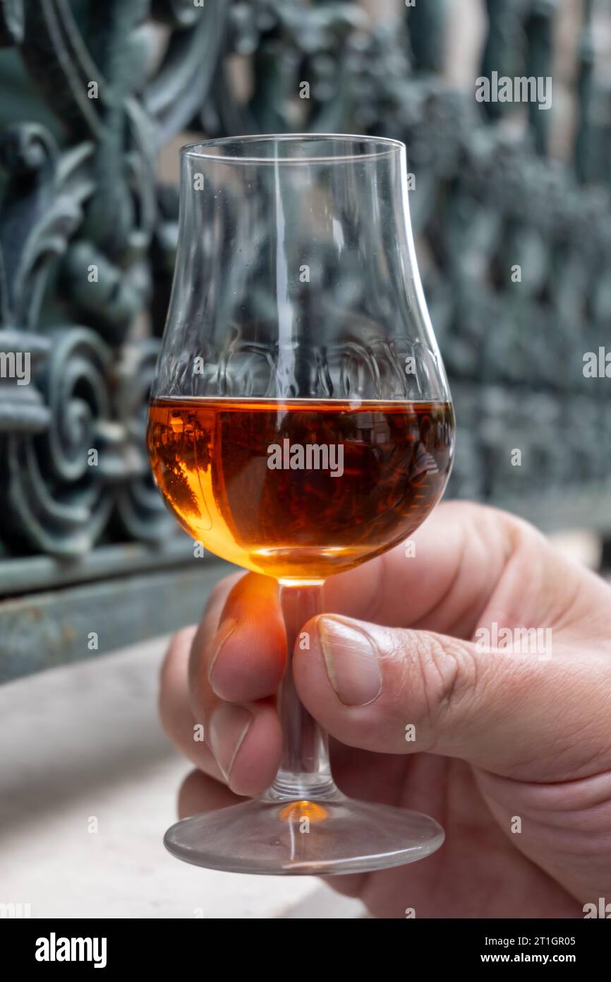 Tasting of aged in barrels cognac alcohol drink and view on old streets ...