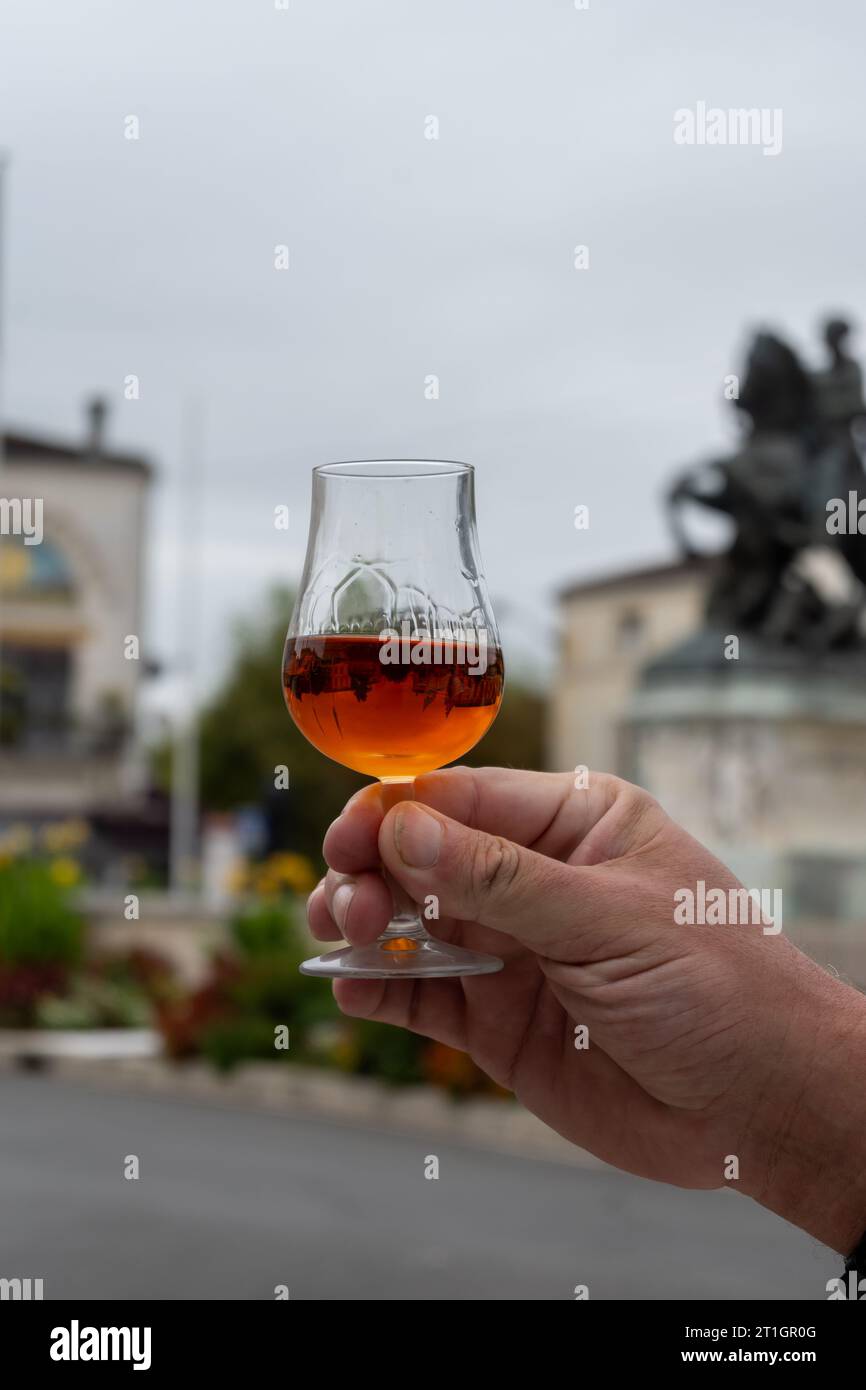 Tasting of aged in barrels cognac alcohol drink and view on old streets ...