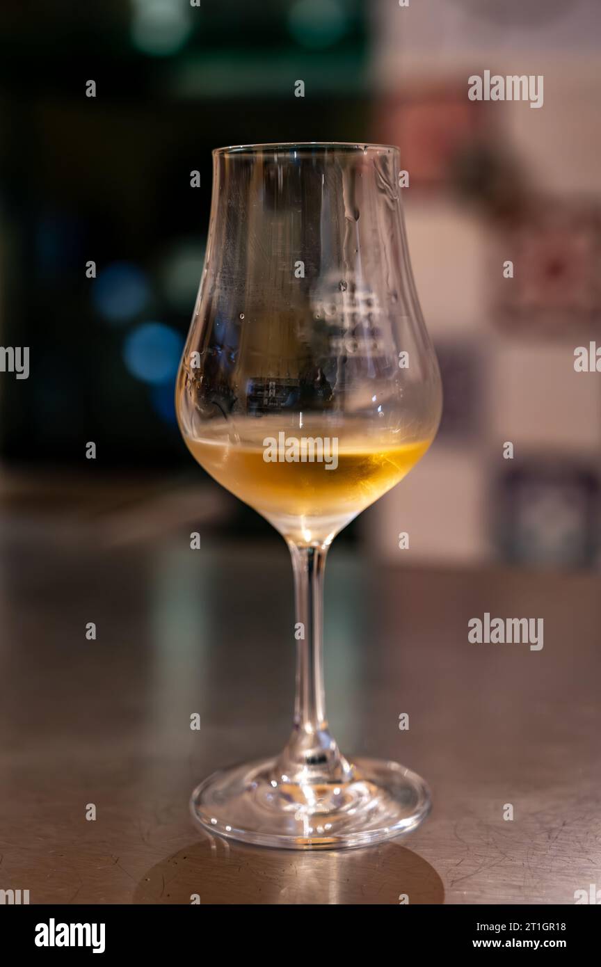 Tasting of cognac spirit aged in old dark French oak barrels in cellar ...