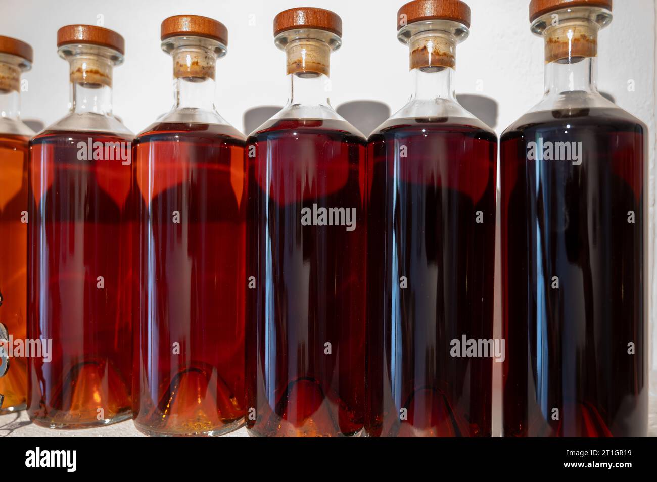 Different colours and ages of cognac spirits in bottles in distillery ...