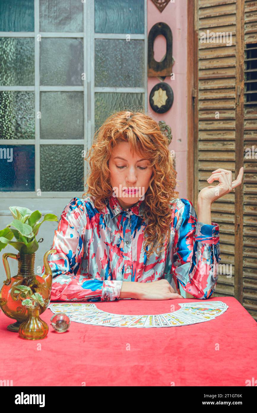 adult Argentine tarot reader woman, sitting at home looking at cards on ...