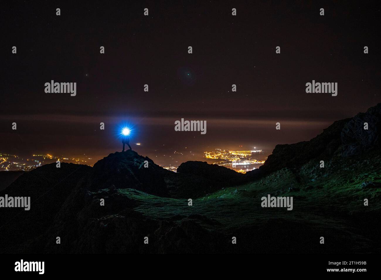Silhouette of a young man with a blue light on Mount Aiako Harria in ...