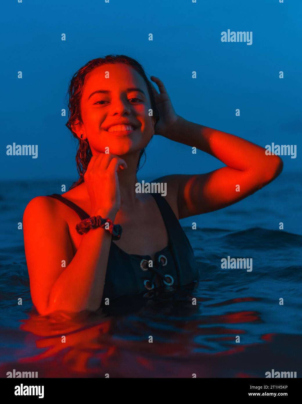 A young pretty Caucasian brunette bathing at night in the sea with an ...
