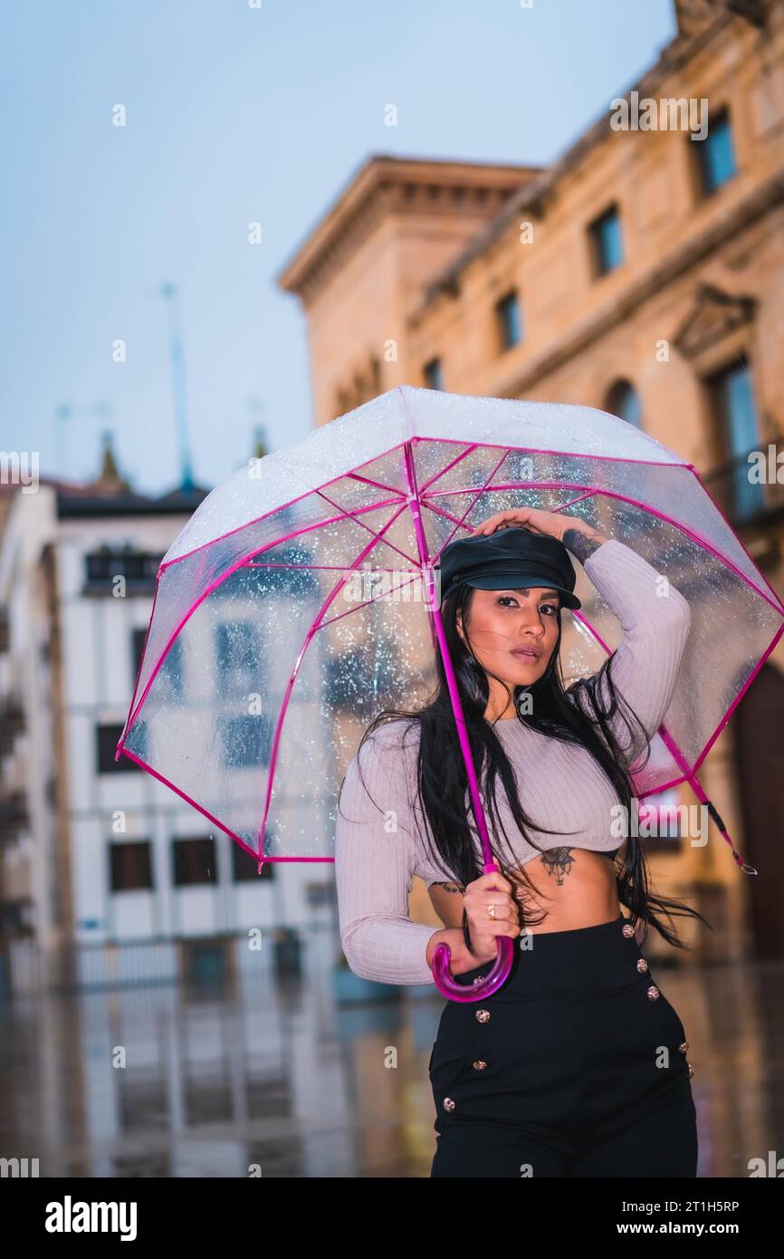 Posing of a young brunette Latina with a leather cap in the autumn rain ...