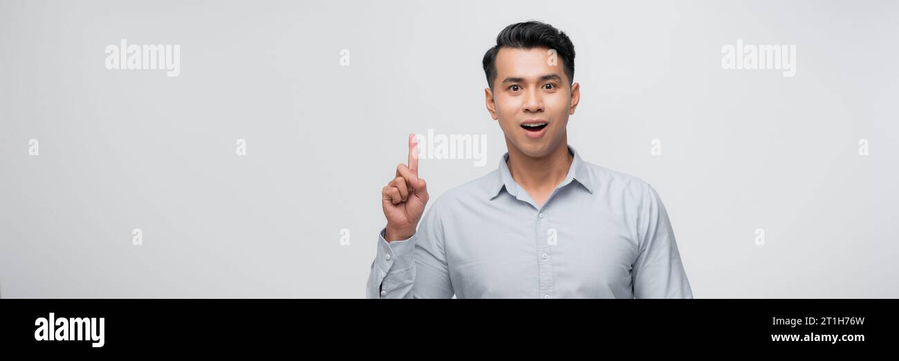 Attractive young man pointing up with his finger isolated on gray ...