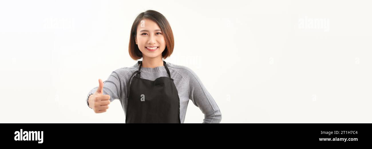 Cheerful young pretty female cafe staff in black apron show support or ...