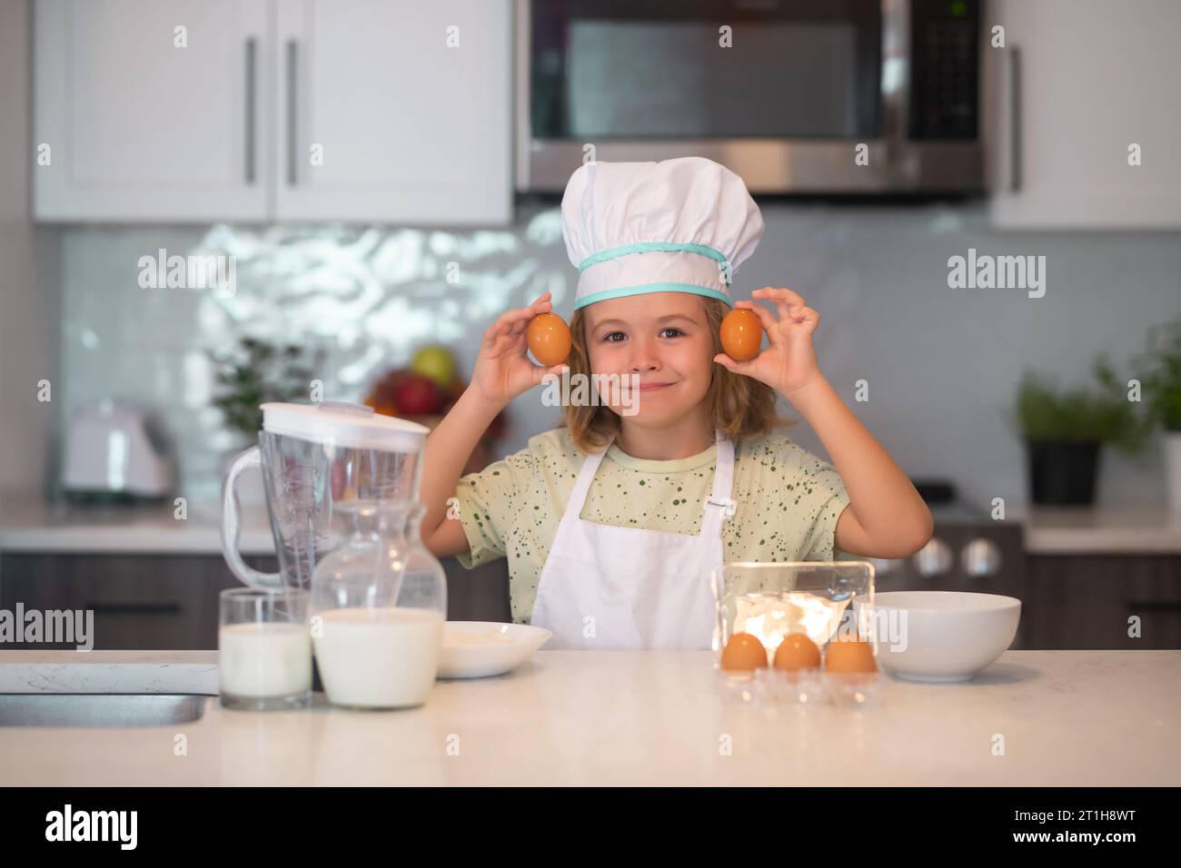 Child chef cook with eggs. Chef kid boy baking on the kitchen. Child ...
