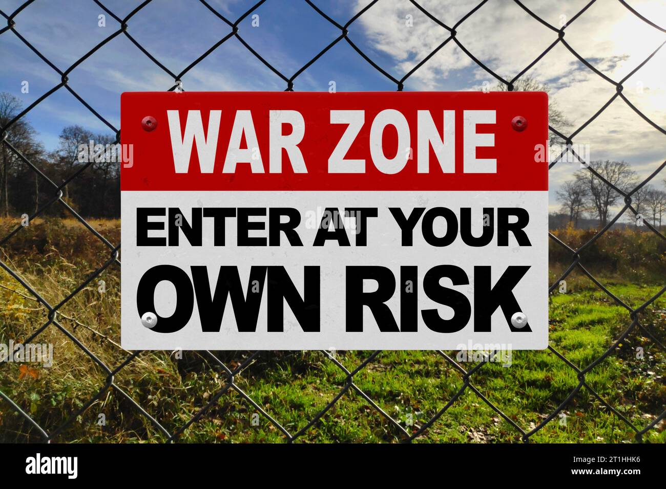 Red an white warning sign on a fence stating in "War zone - Enter at ...