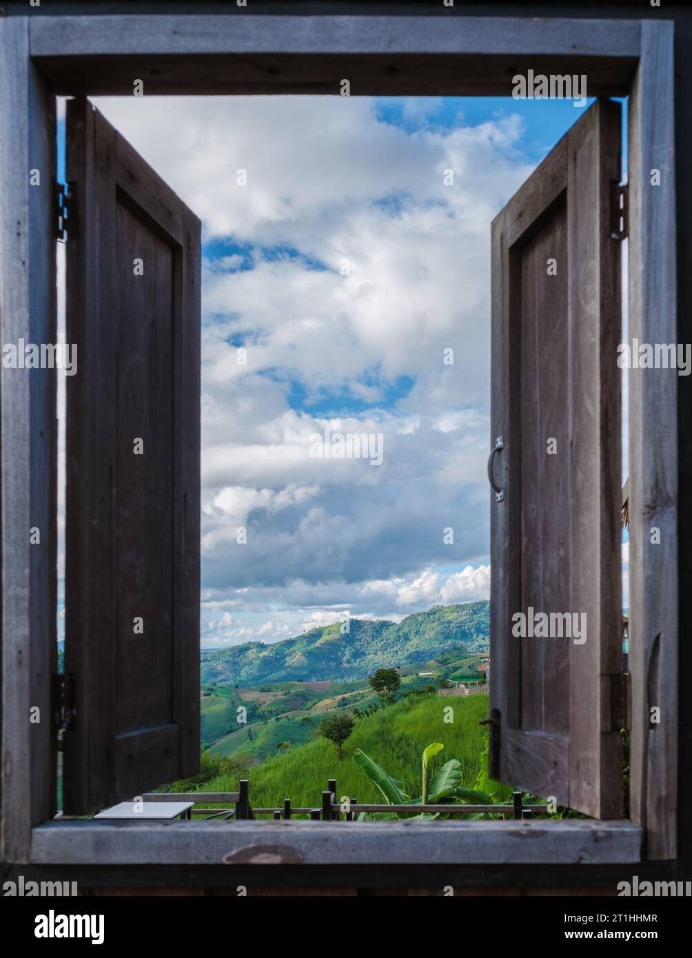 a view trough a wooden window at the green mountains of Doi Chang ...