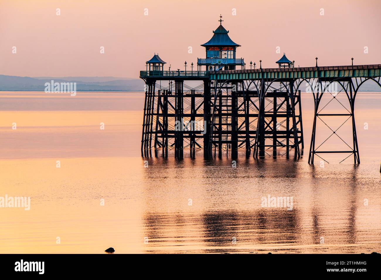 Pier with its legs reflecting onto a calm sea Stock Photo - Alamy