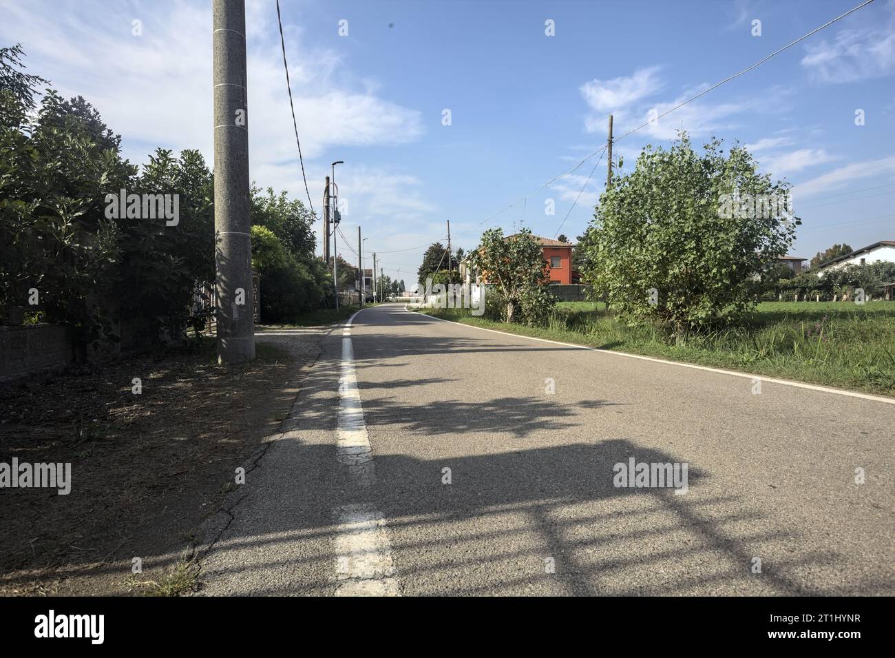 Narrow road borderd by wooden poles and over head cables in a small ...