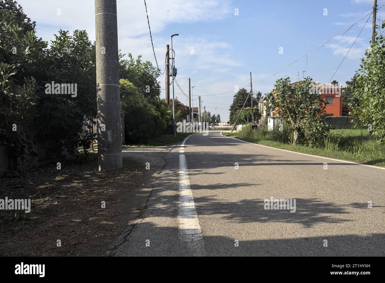 Narrow road borderd by wooden poles and over head cables in a small ...