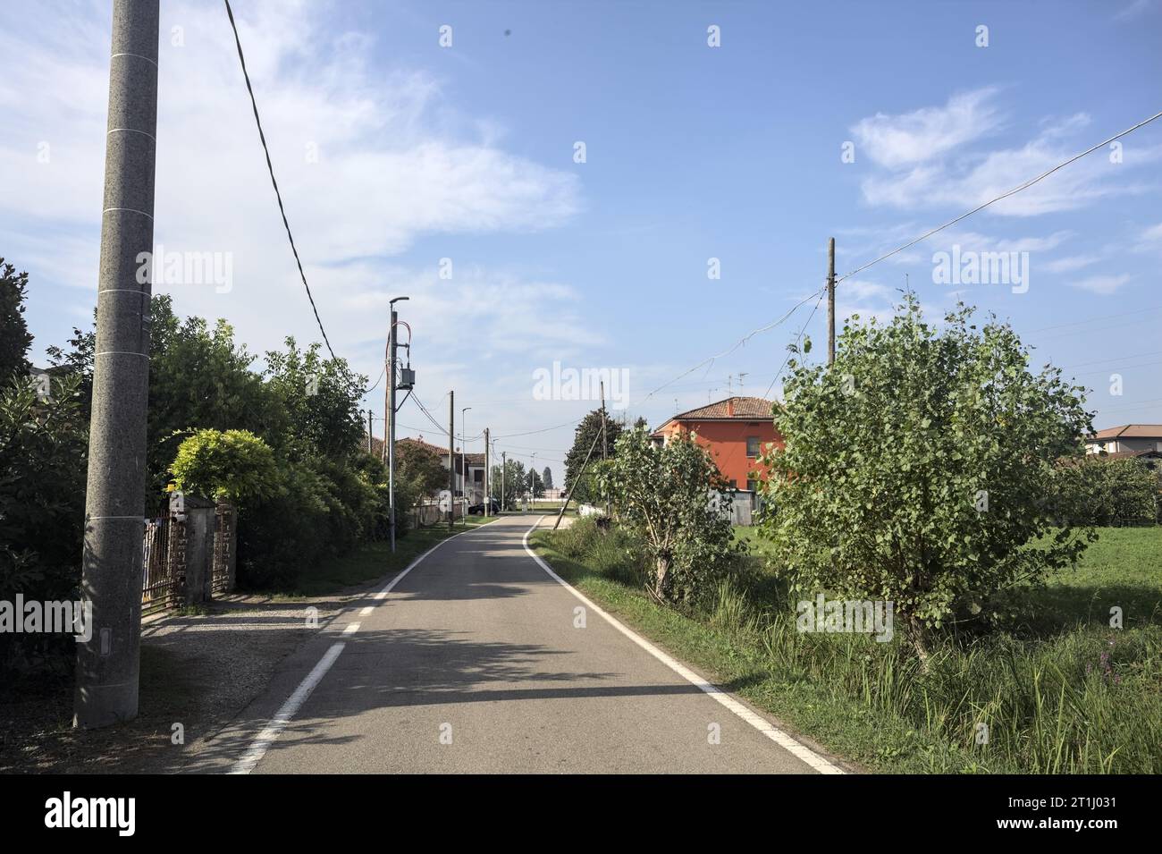 Narrow road borderd by wooden poles and over head cables in a small ...