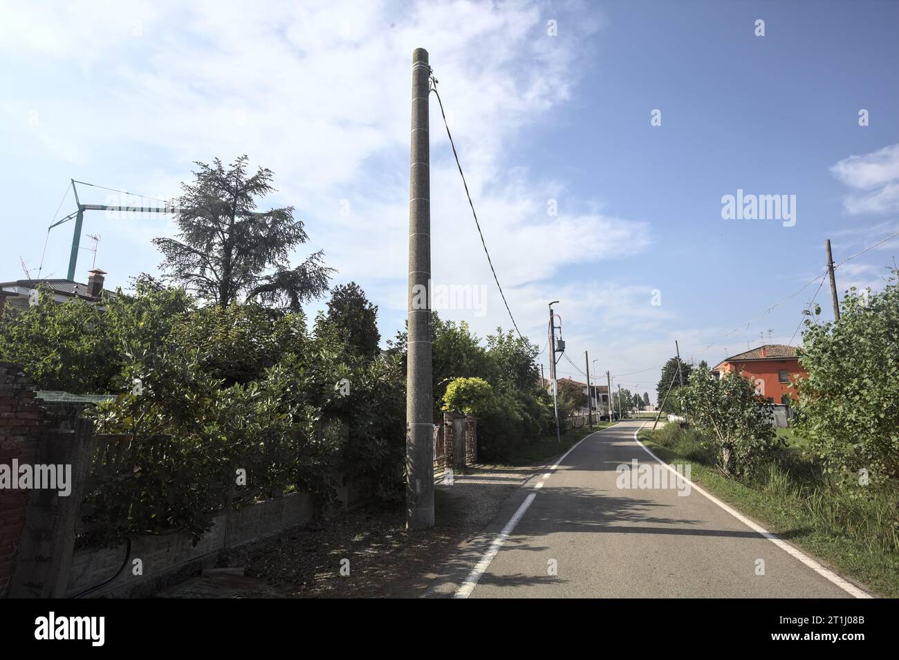 Narrow road borderd by wooden poles and over head cables in a small ...