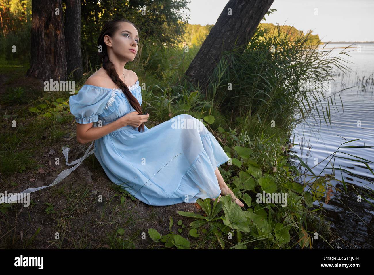 sad girl in a blue dress thinks about suicide by the lake Stock Photo ...