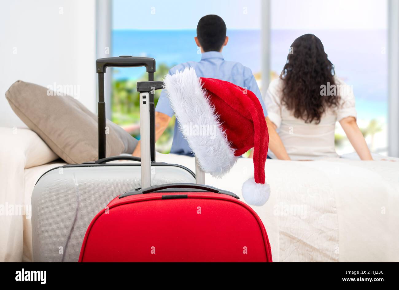 A red suitcase, a Santa Claus hat and couple of tourists relaxing ...