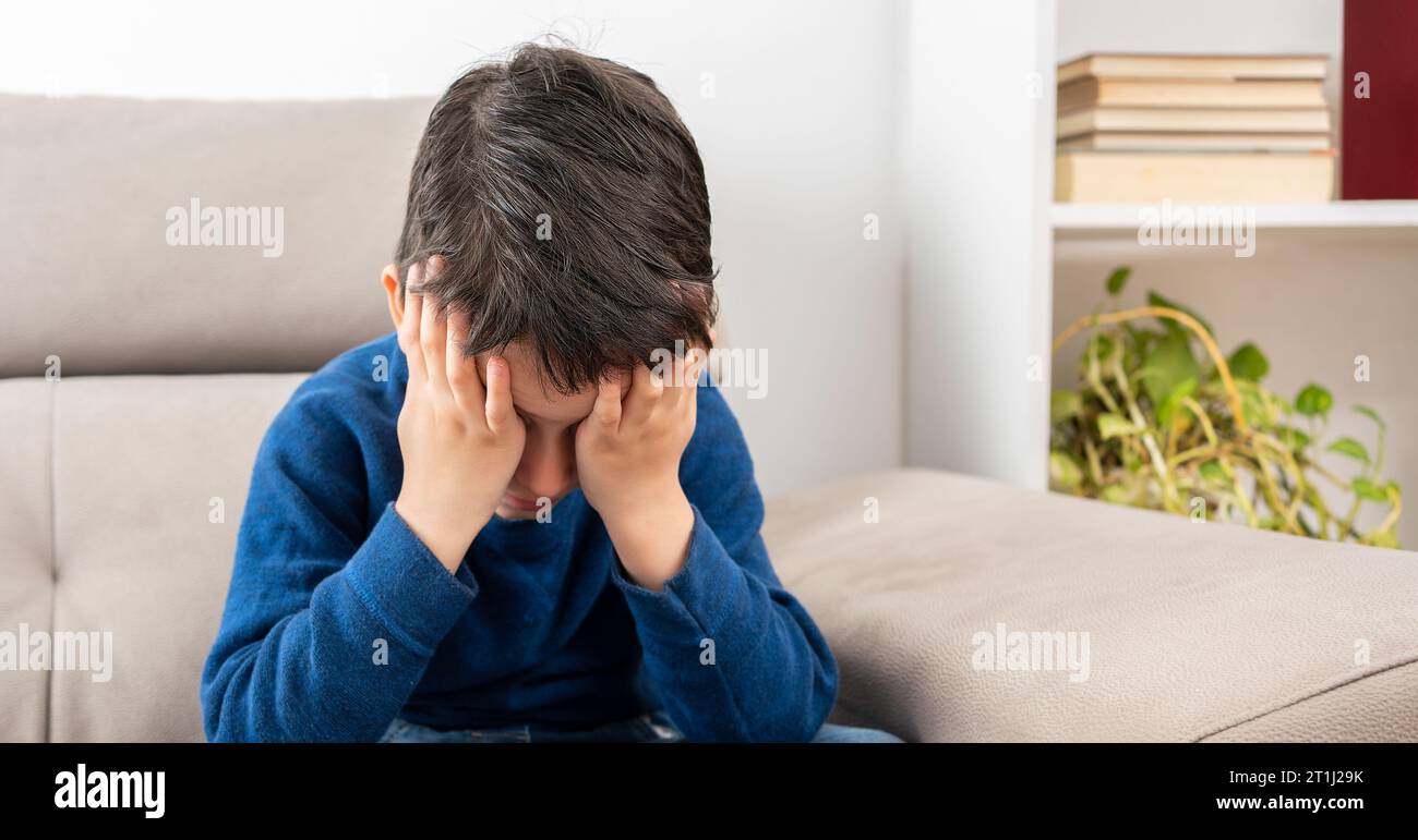 Upset problem boy with head in hands sitting on sofa concept for ...